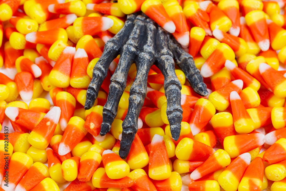 Scary skeleton hand coming out of pile of candy corn Stock Photo ...