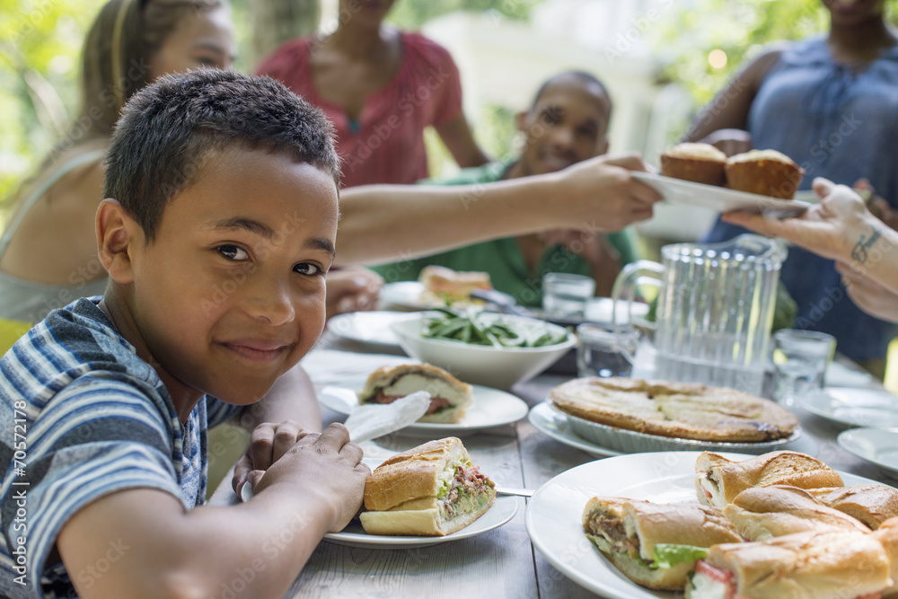 A family gathering; men; women and children around a table in a garden ...