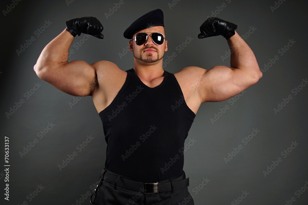Muscular soldier poses and shows his biceps Stock Photo | Adobe Stock