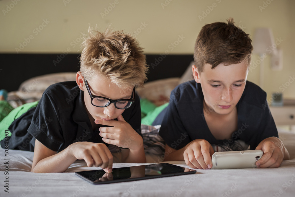 Two boys lying on bed using digital tablet Stock-Foto | Adobe Stock