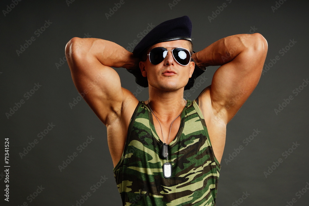 Foto de Muscular young military man poses with his hands behind the ...