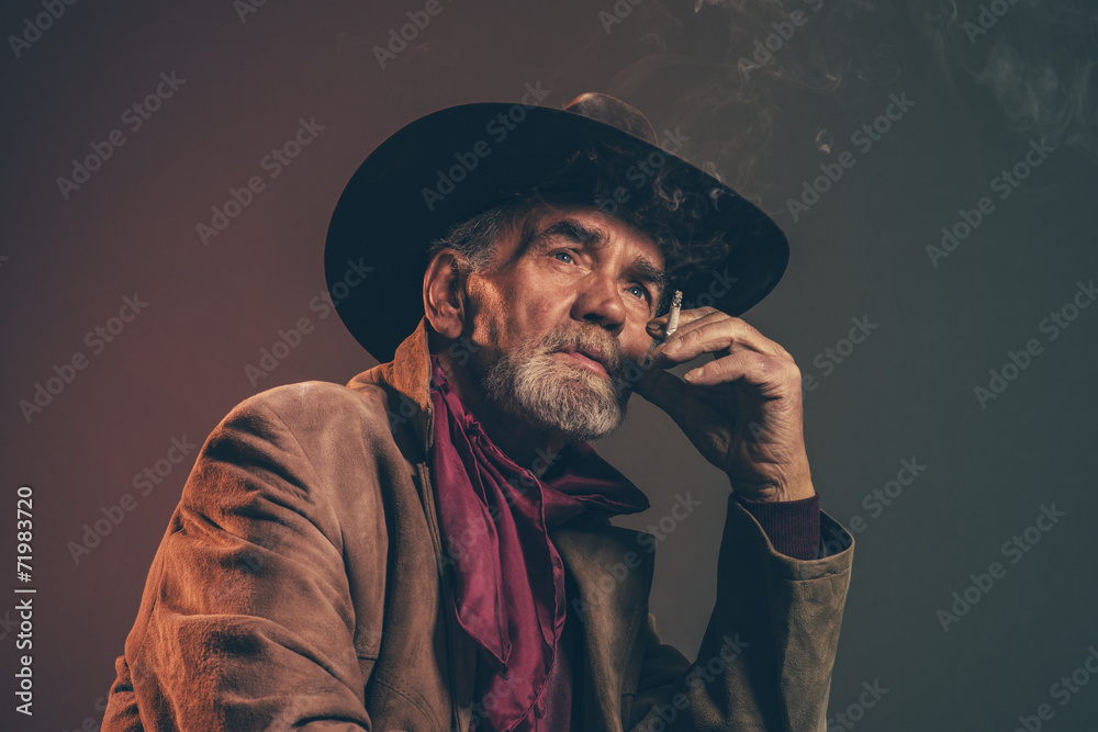 Old rough western cowboy with gray beard and brown hat smoking a 스톡 사진 ...