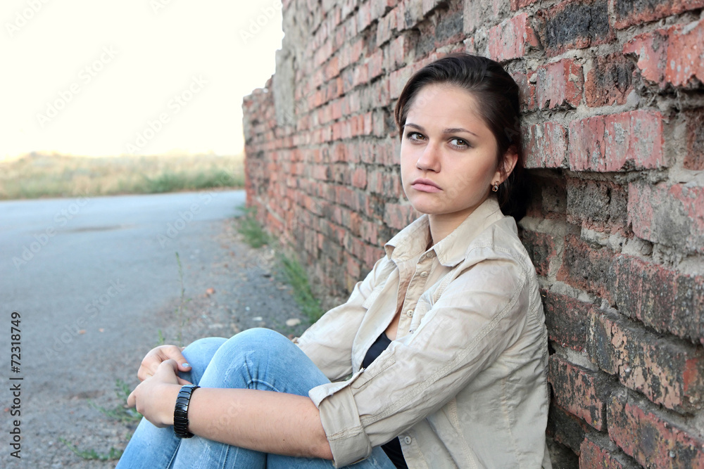 Sad Girl Sitting Against Wall