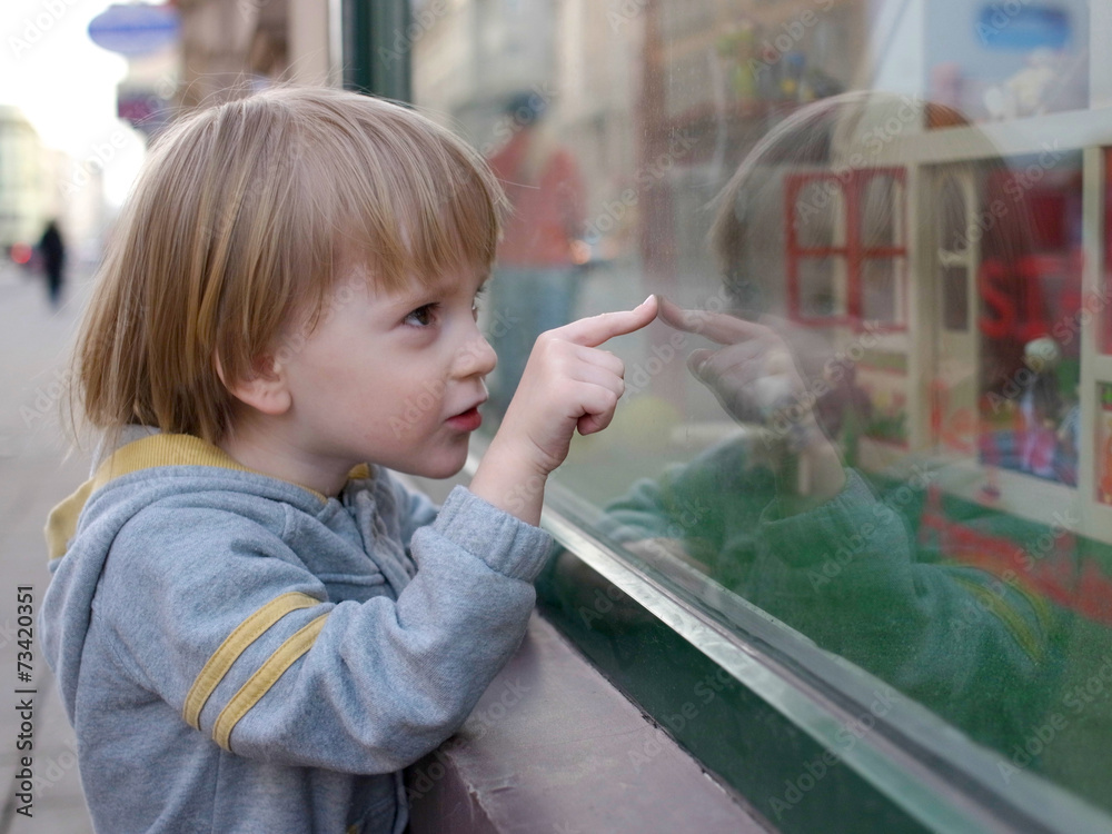 Boy pointing a favorite toy through the showcase Stock Photo | Adobe Stock