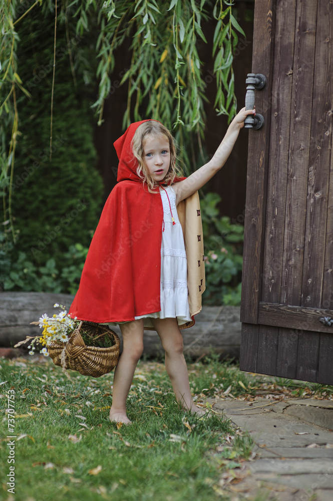 Cute blonde girl playing little red riding hood in the garden Stock ...