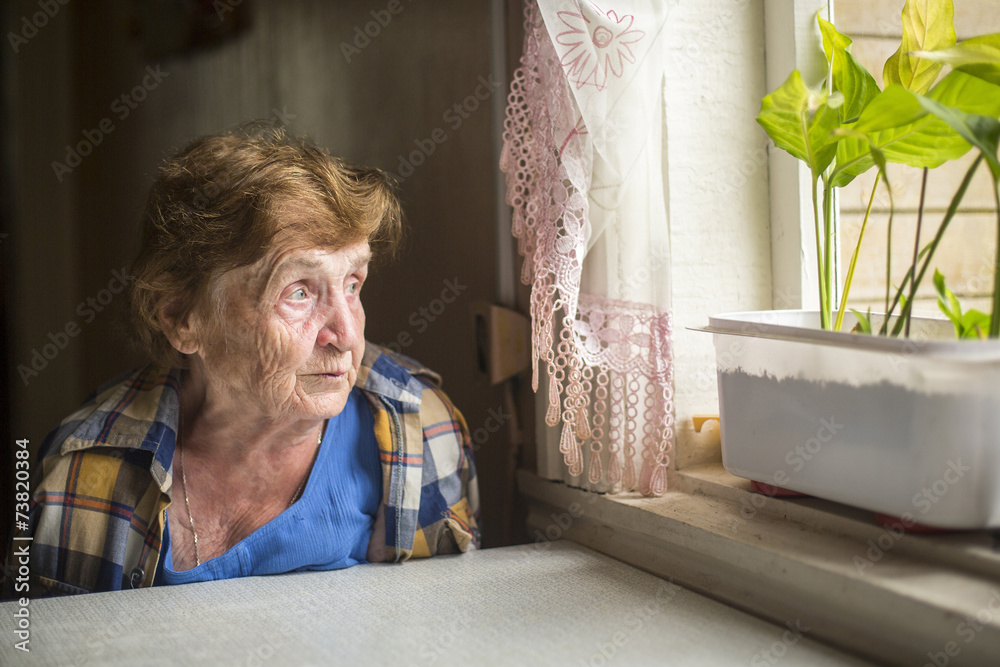 Old woman sitting alone near the window in his house. Stock Photo ...