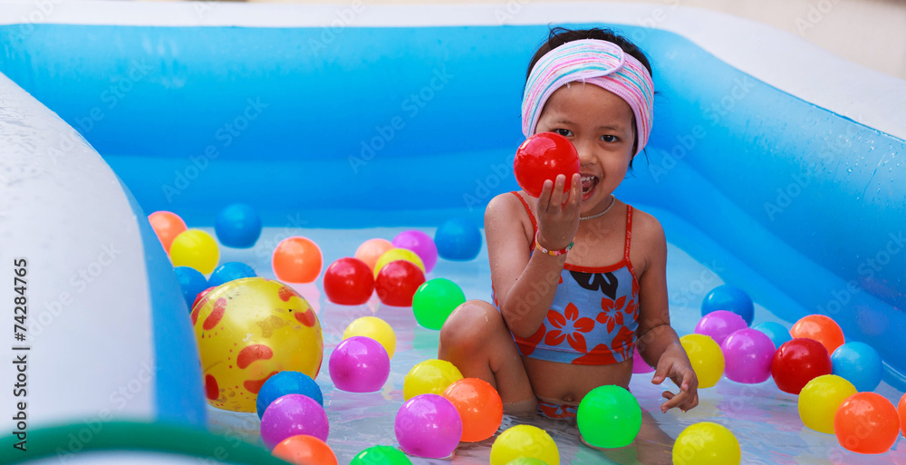 Little girl playing ball in the kiddie pool. Stock Photo | Adobe Stock