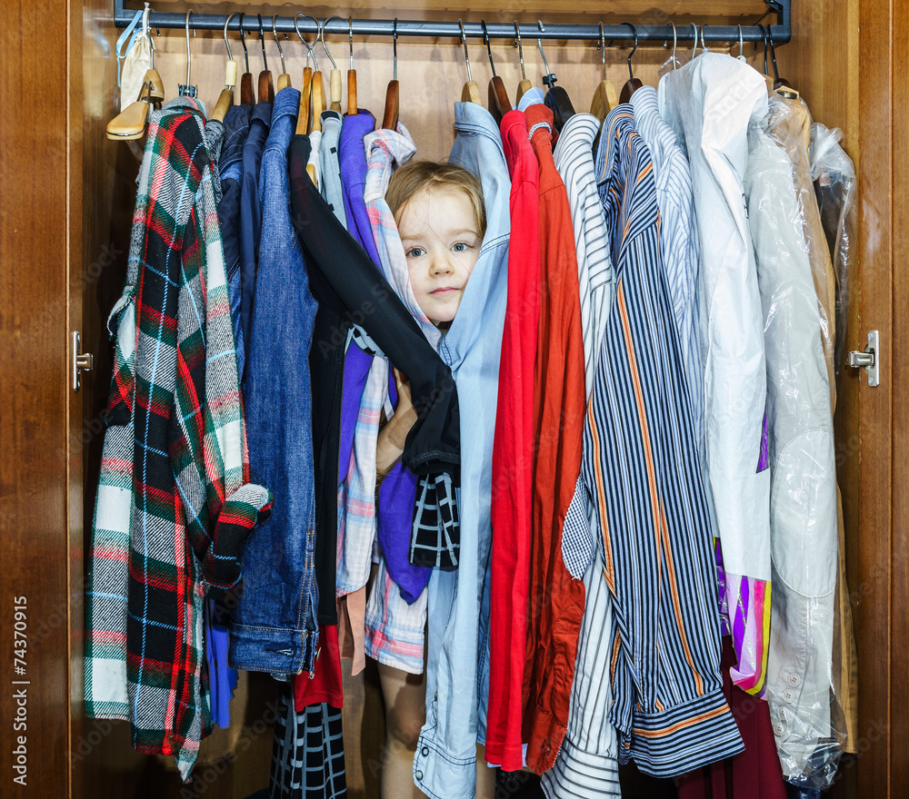 Cute little girl hiding inside wardrobe from her parents Stock Photo ...