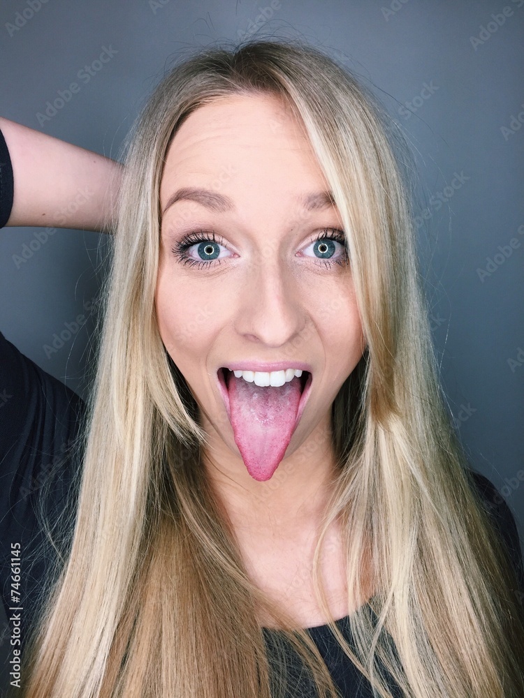 junge Frau streckt Zunge raus Stock-Foto | Adobe Stock