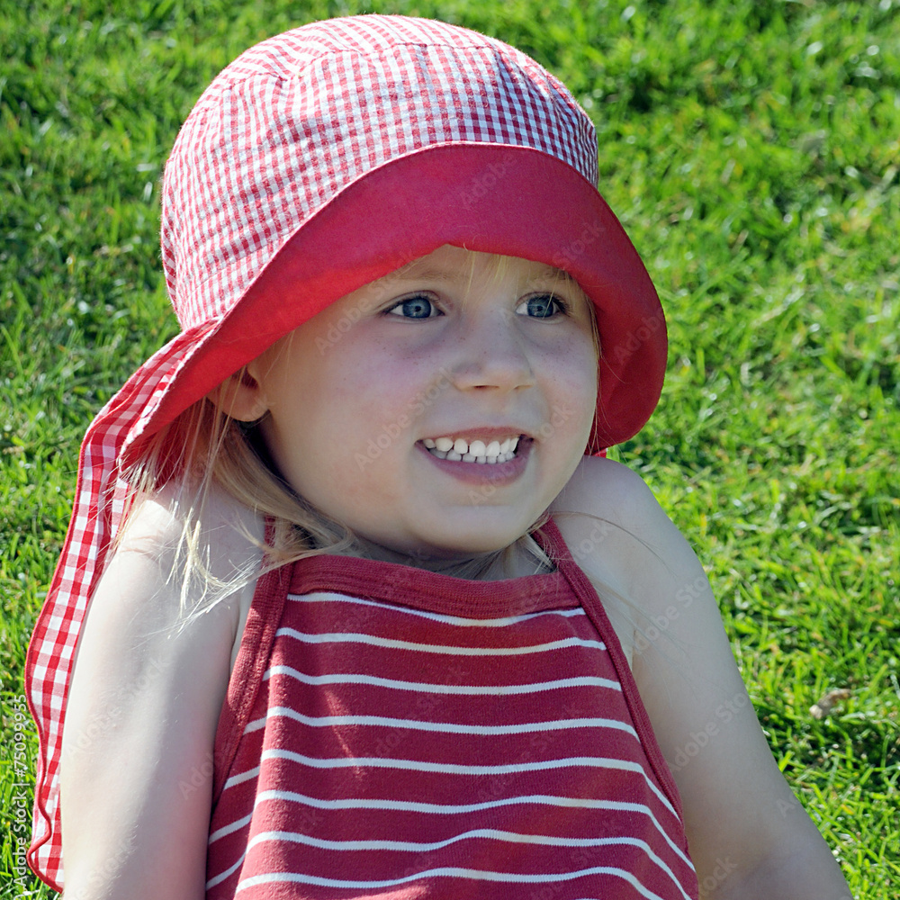 Kind lacht und sitzt auf Wiese Stock-Foto | Adobe Stock