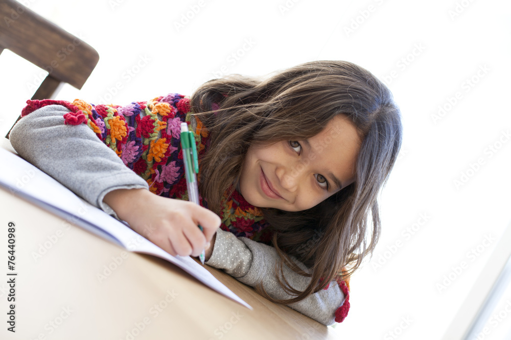 Niña con poncho de colores escribiendo Stock Photo | Adobe Stock