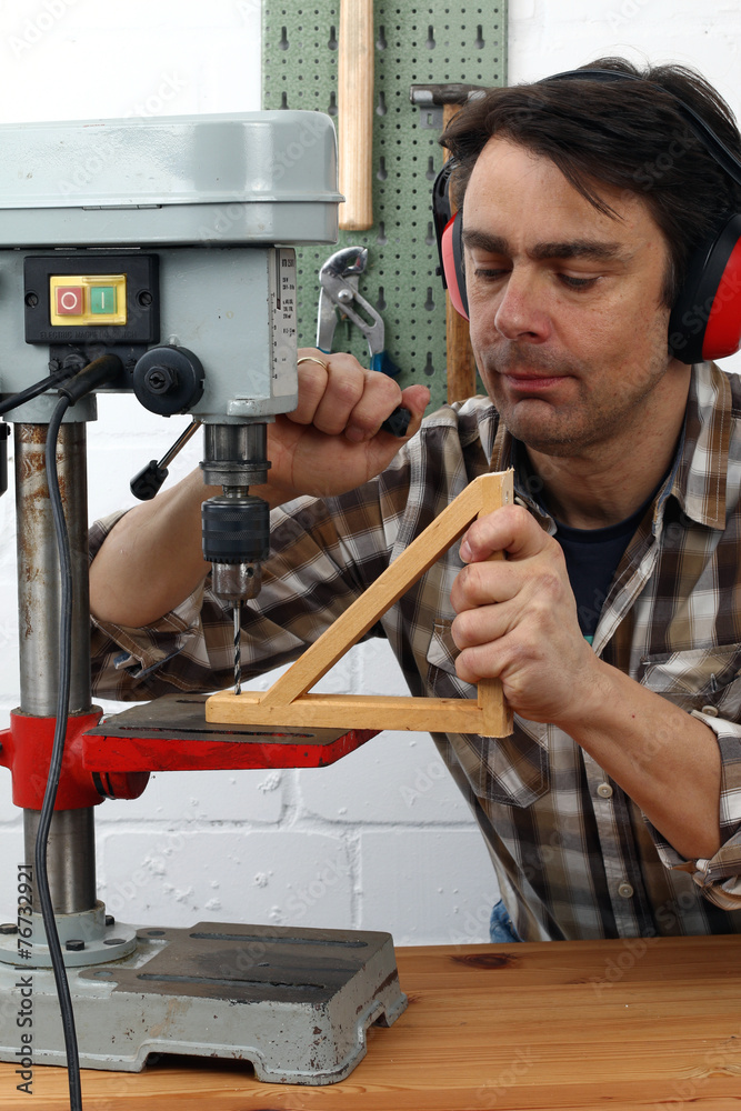 Handwerker bohrt konzentriert mit Standbohrer Stock-Foto | Adobe Stock