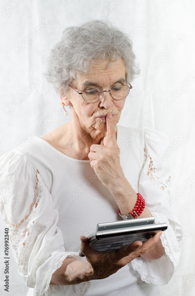 alte Frau schaut erstaunt auf Taschenrechner Stock-Foto | Adobe Stock