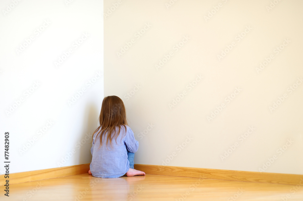 Sad little girl sitting in a corner Stock Photo | Adobe Stock