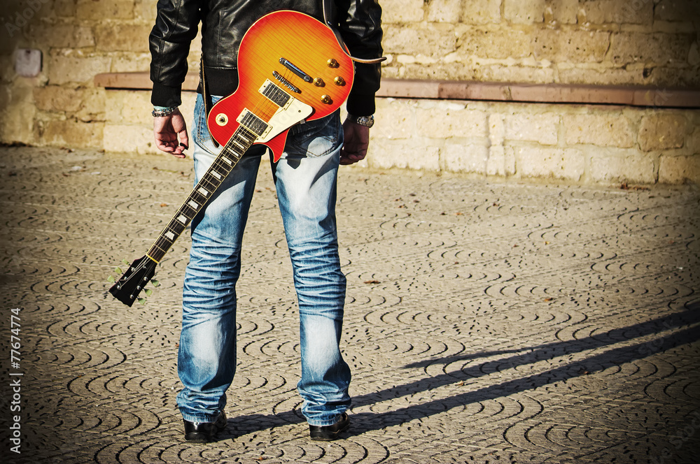 back view of a guitarist standing with a guitar Stock-Foto | Adobe Stock