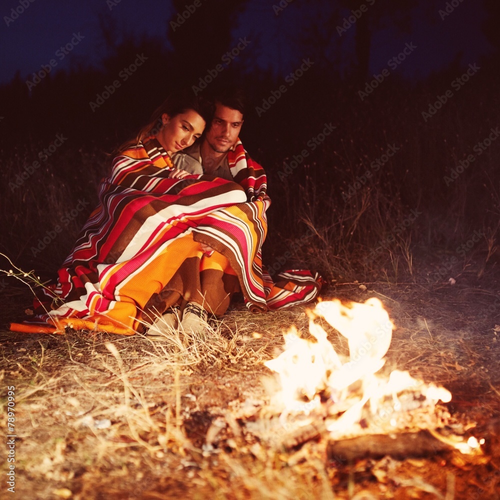 a charming couple sitting around the campfire Stock Photo | Adobe Stock