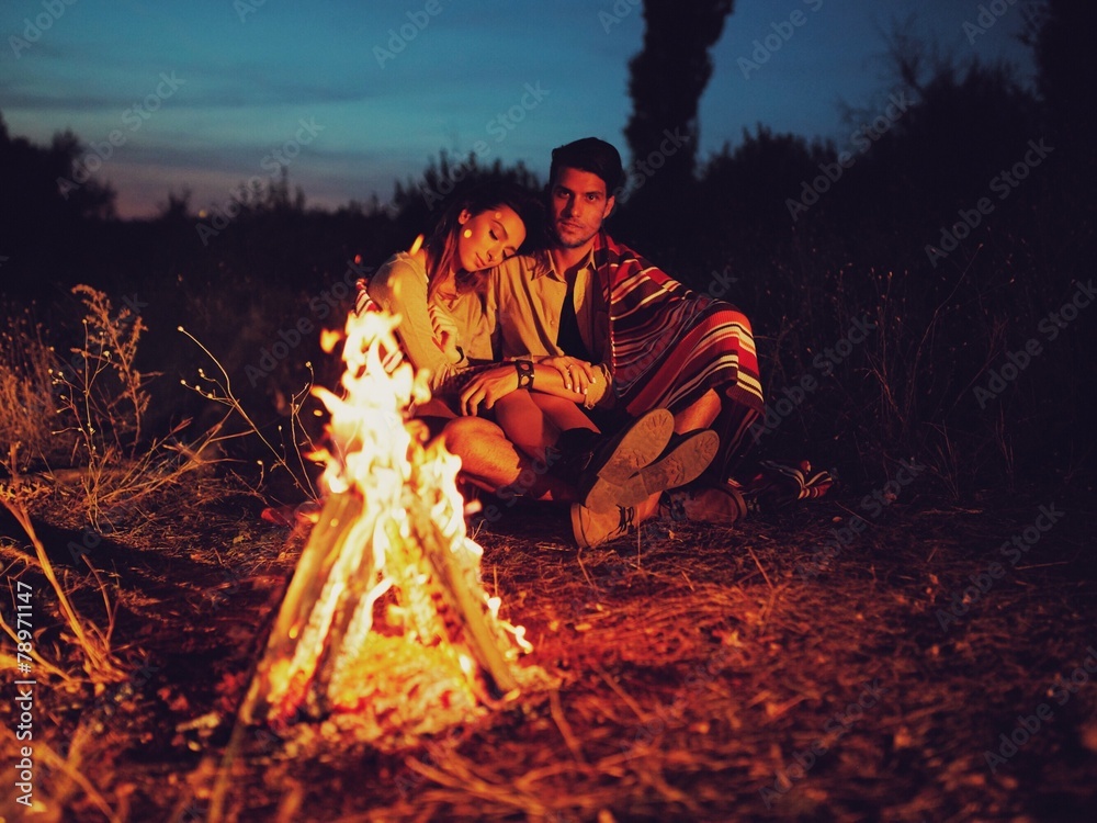 a charming couple sitting around the campfire Stock Photo | Adobe Stock