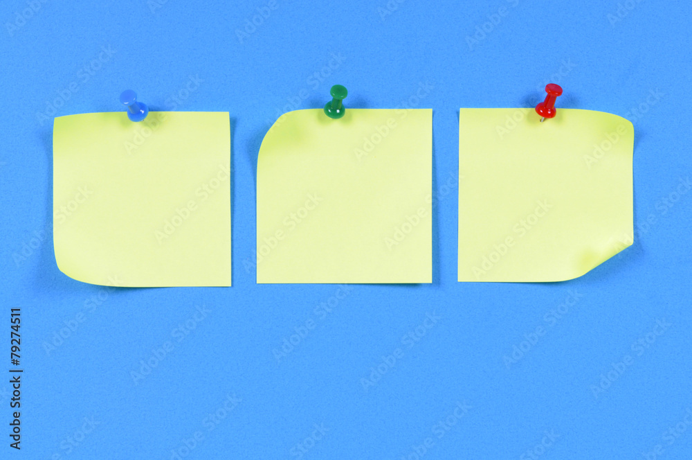 Row or line of three yellow post it style sticky note pinned to blue ...