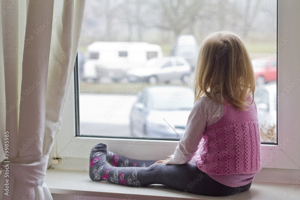 Little girl sitting on window sill looking out of window Stock Photo ...