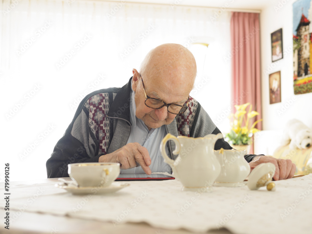 Old man sitting at table using digital tablet Stock-Foto | Adobe Stock
