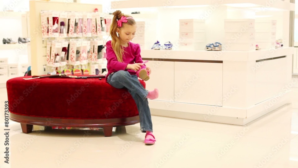Little girl sitting and tries on the pink shoes in a shoe store vídeo ...