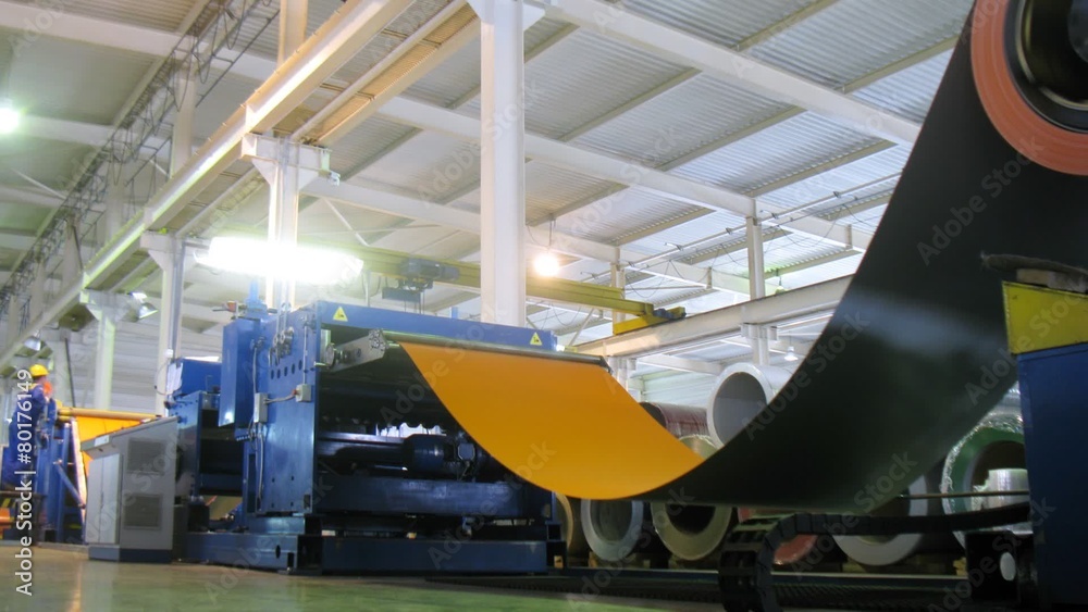 Wide sheets of metal are braided in big rolls at plant, time lapse ...