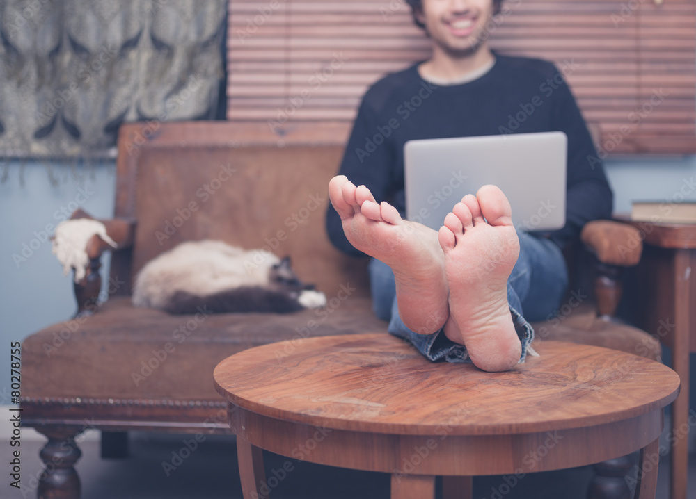 Barefoot man working on laptop Stock Photo | Adobe Stock