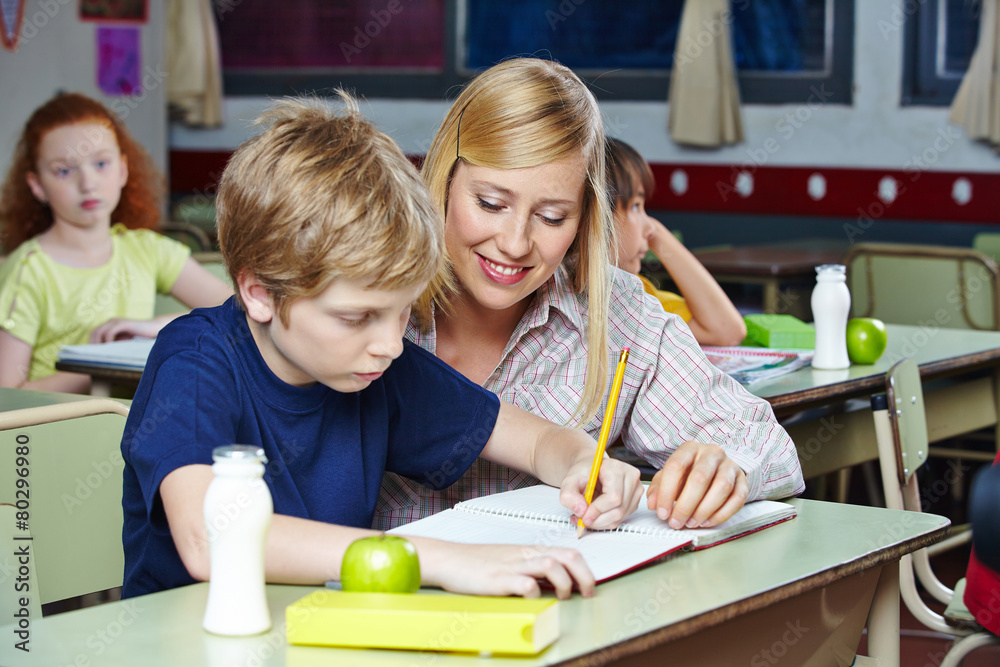 Teacher helping student in classroom Stock Photo | Adobe Stock
