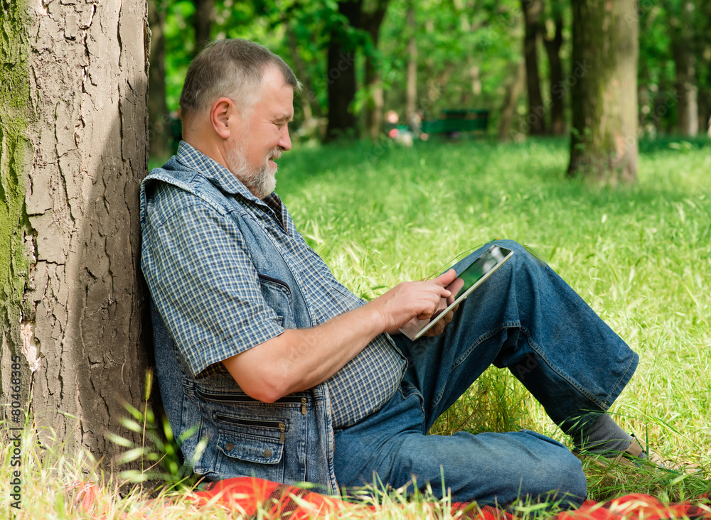 old man sitting under a tree with the tablet Stock Photo | Adobe Stock
