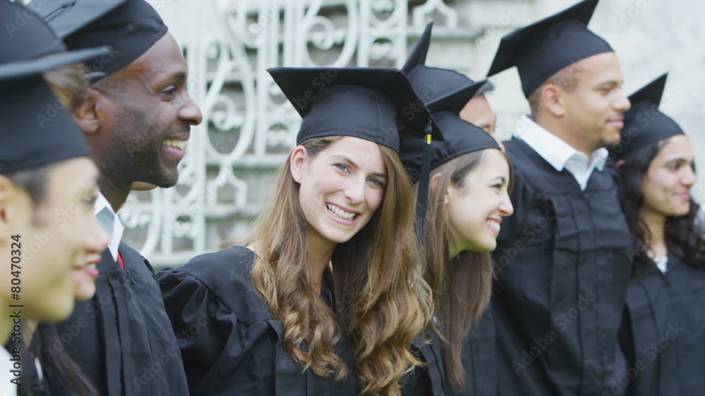 Happy students on graduation day stand in a line and pose for ...