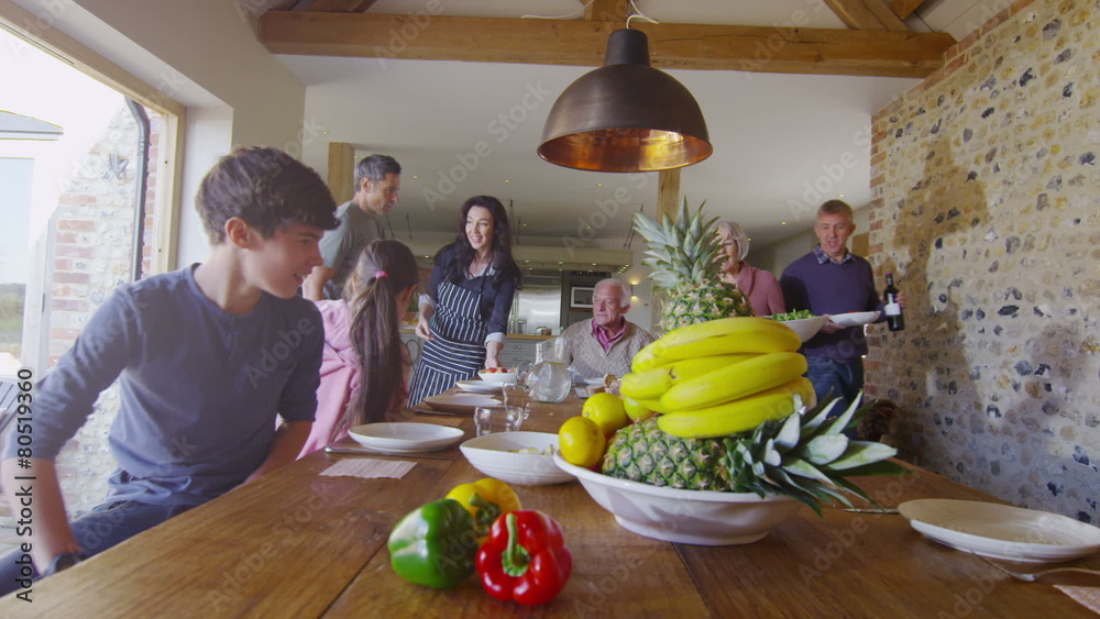 Happy extended family group sit down to enjoy a meal together at home ...