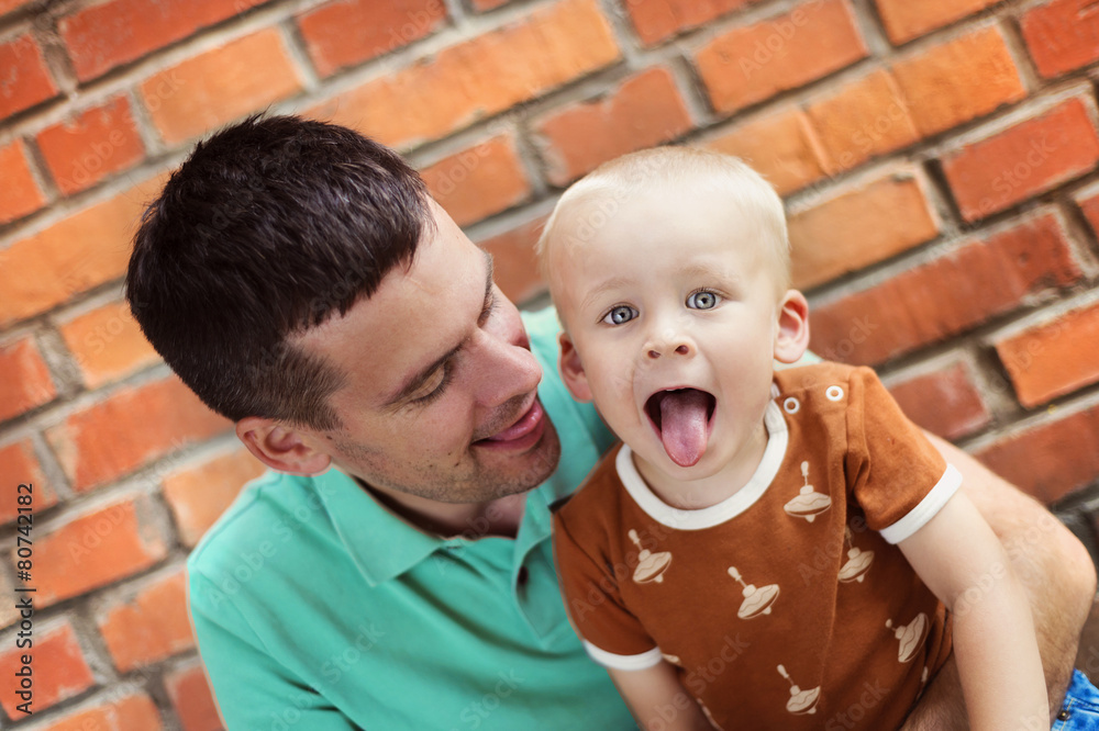 Father and son making funny faces on a brick wall background Stock ...