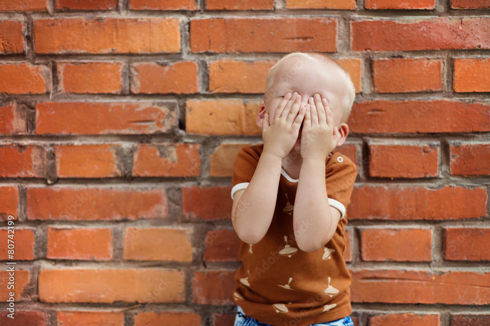 Cute little boy making funny faces on a brick wall background Stock ...