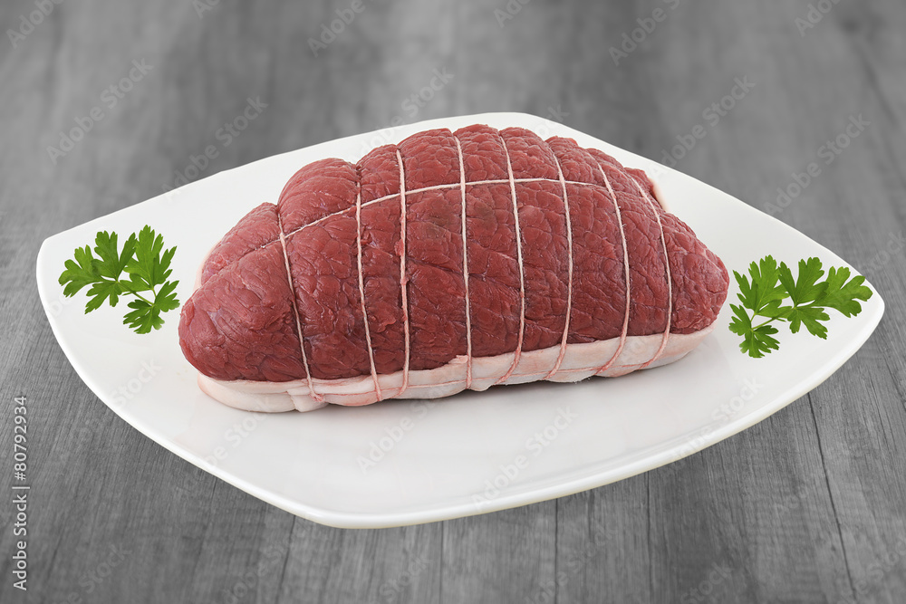 rosbeef cru présenté sur assiette fond en bois Photos | Adobe Stock