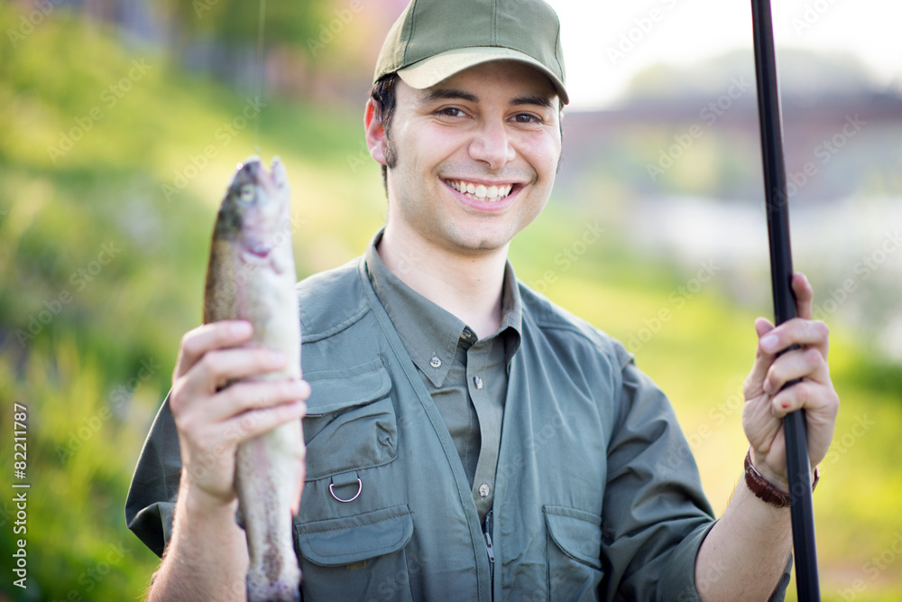 Smiling fisherman holding a fish Stock Photo | Adobe Stock