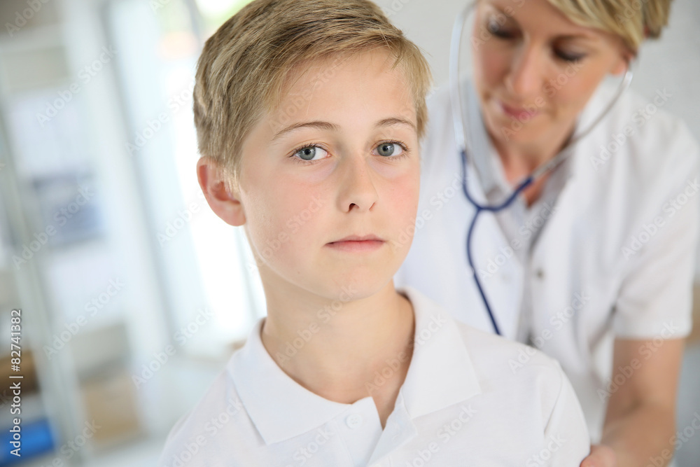 Doctor examining 12-year-old boy with stethoscope Stock Photo | Adobe Stock