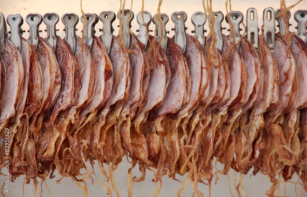 Stock Photo - Close up dried squid hanging in row waiting for cu Stock ...