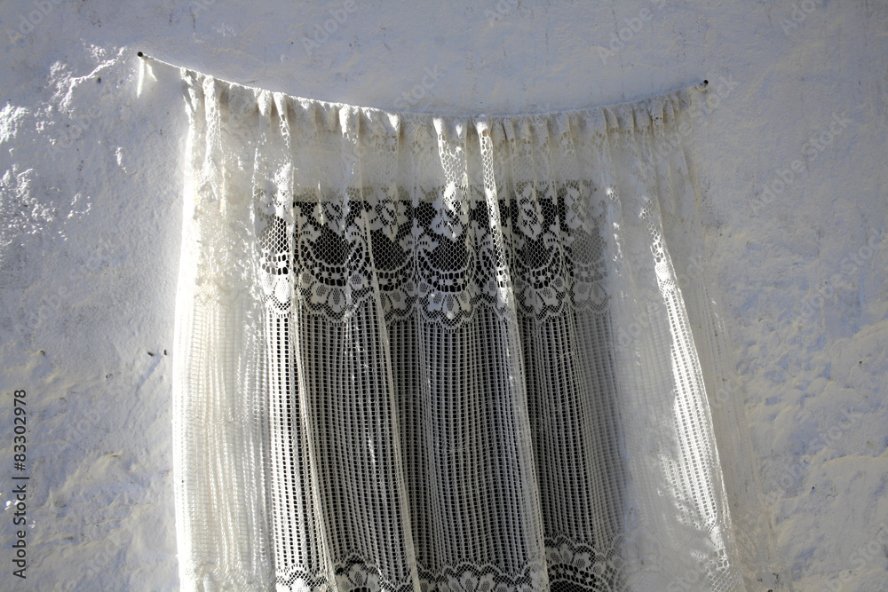 White lace curtain on a rustic white wall. Stock Photo | Adobe Stock