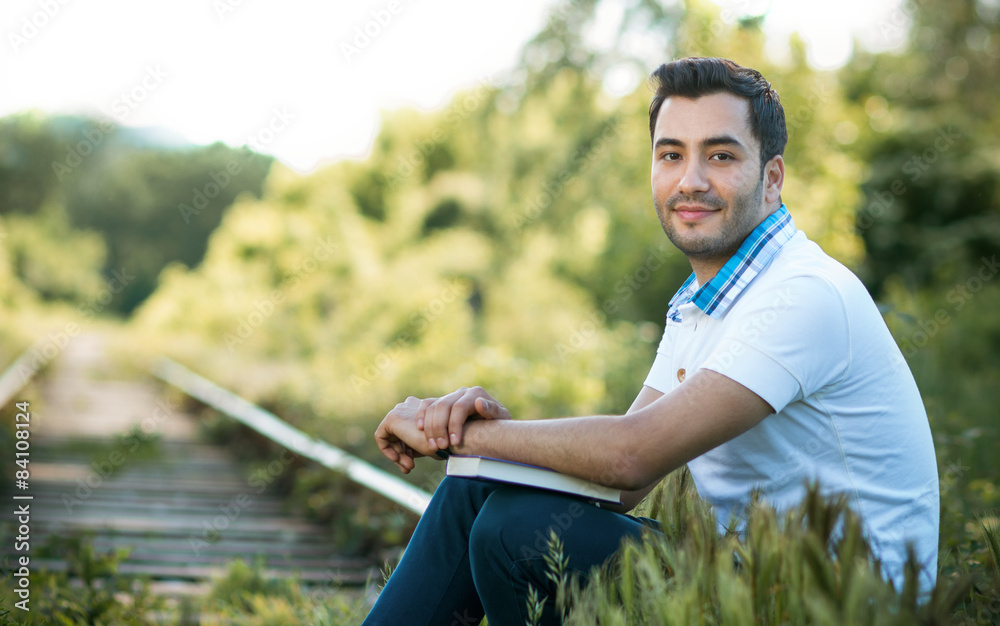 Man sitting on train lines in forest. Daylight, outdoors Stock Photo ...