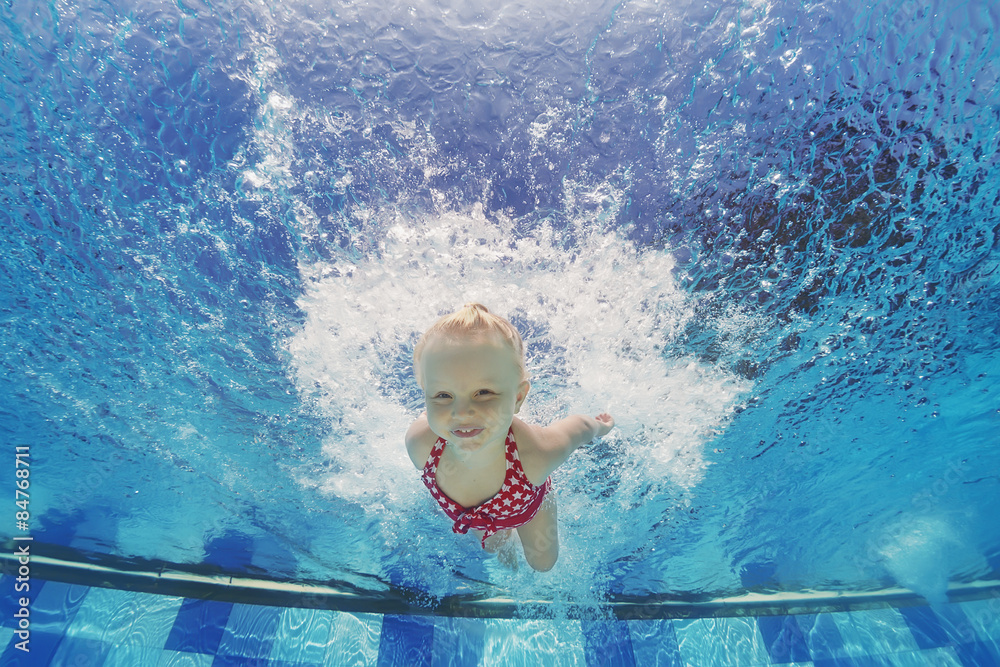 Baby girl swimming and diving in pool with fun - jumping deep down ...