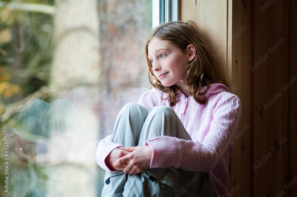 tween age girl sitting an looking out a window Stock Photo | Adobe Stock