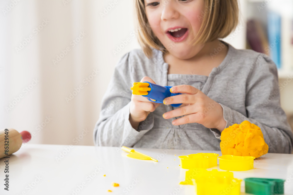 Little girl playing with yellow modeling clay Stock Photo | Adobe Stock