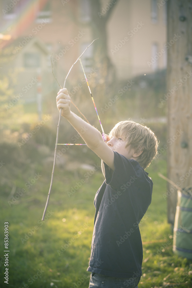 Boy using bow self-built of twigs and looms Stock Photo | Adobe Stock