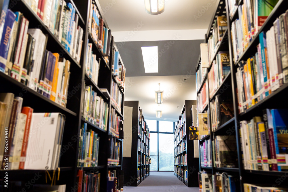 Library book shelf aisles at low angle with focus on window with ...