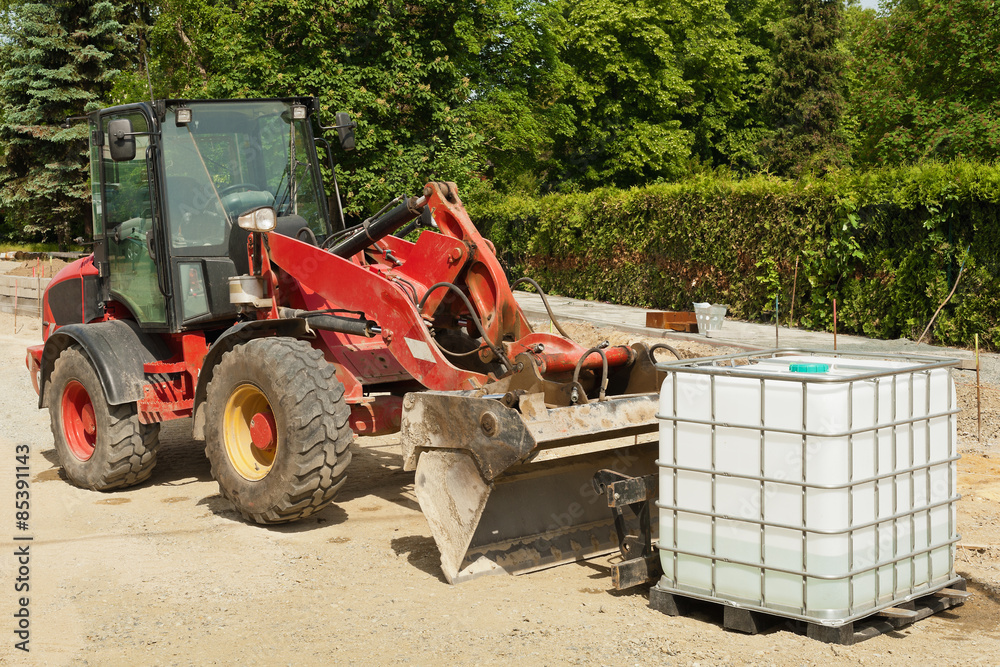 Ein roter Radlader steht neben einem Tank für Bauwasser Stock-Foto ...