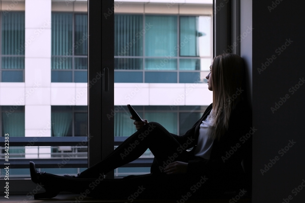 Sad girl sitting alone in front of window Stock Photo | Adobe Stock