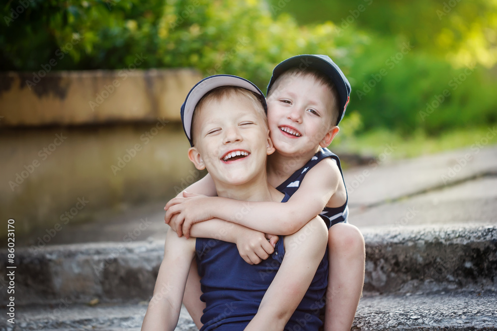 Two adorable little brothers laughing and hugging on warm and sunny day ...