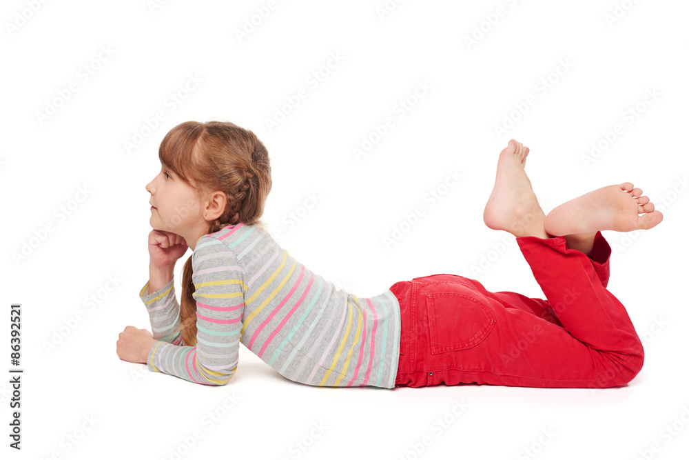 Side view of smiling child girl lying on stomach on the floor with ...