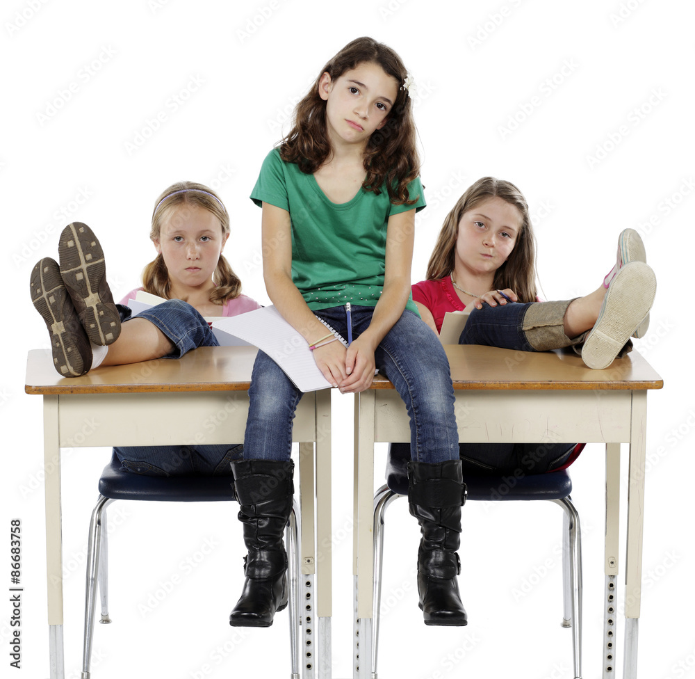 Studio shot isolated on white of three bored tween girls sitting at and ...