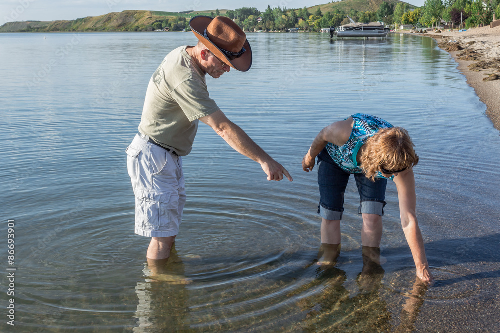 man and woman standing in water with the man pointing at something in ...